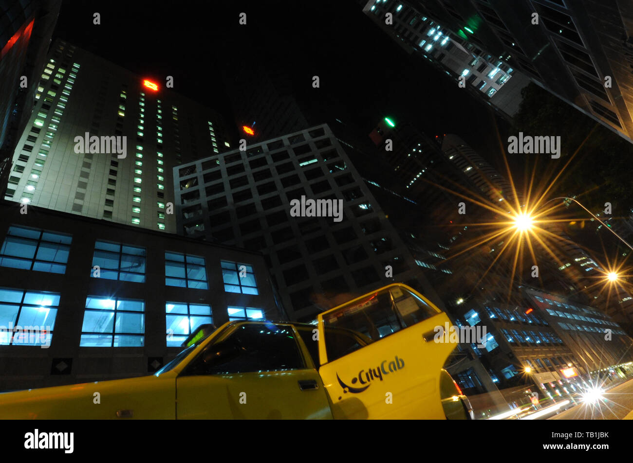 Low angle shot of a yellow taxi cab stopping along the roadside opening ...