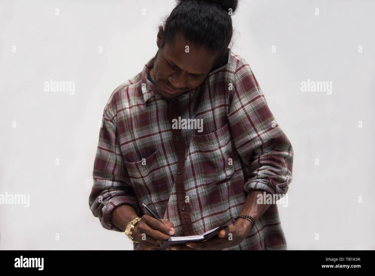 front view of black man taking notes while talking on phones, young ...