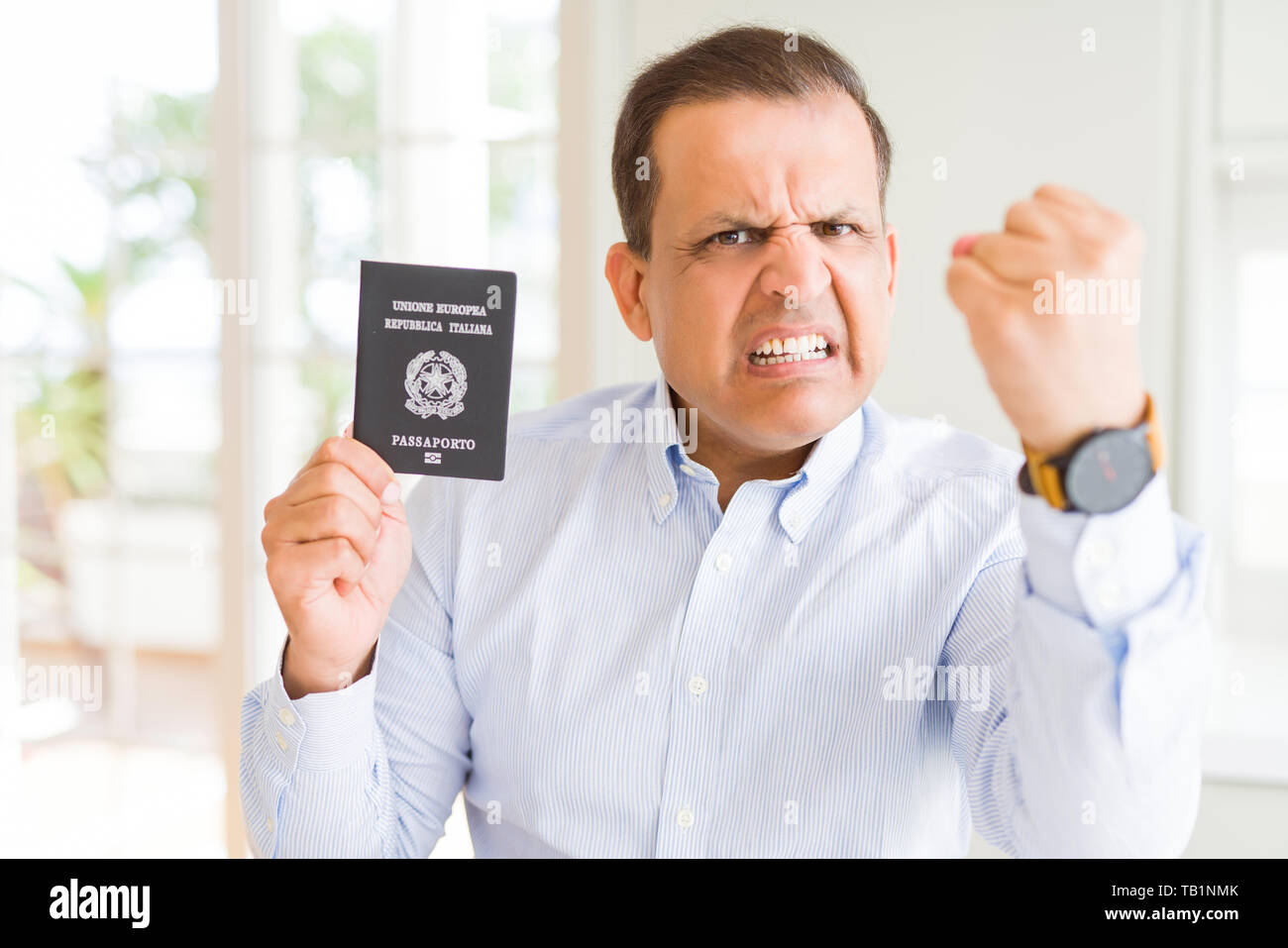 Middle age man holding holding passport of Italy annoyed and frustrated ...