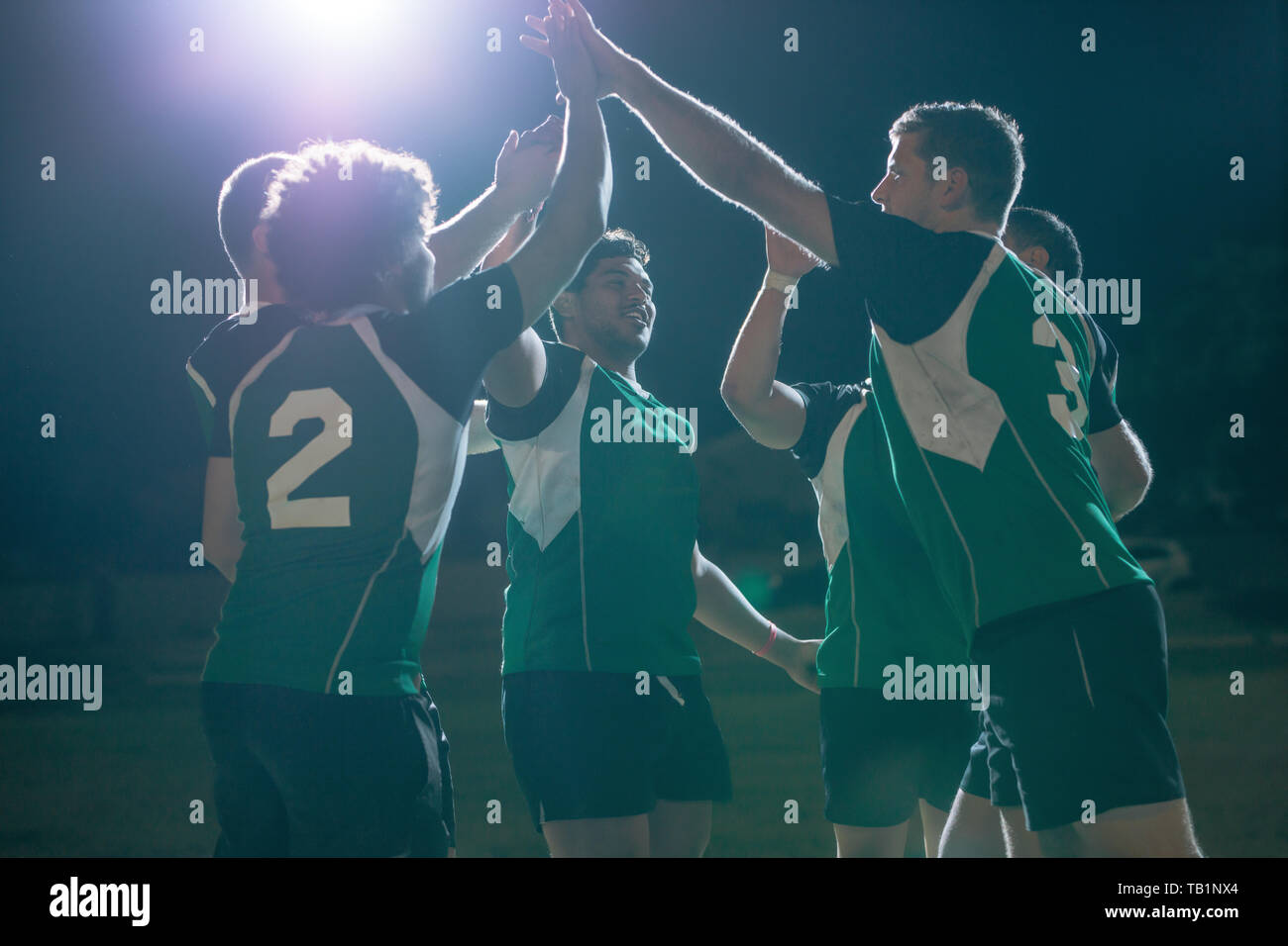rugby team putting their hands together after victory under lights ...