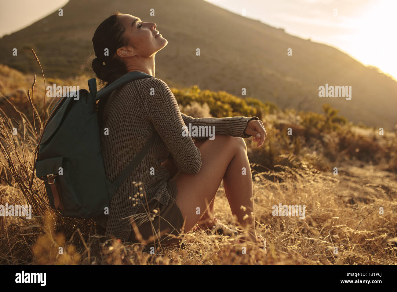 Young woman hiking in countryside sitting and taking rest. Female hiker ...