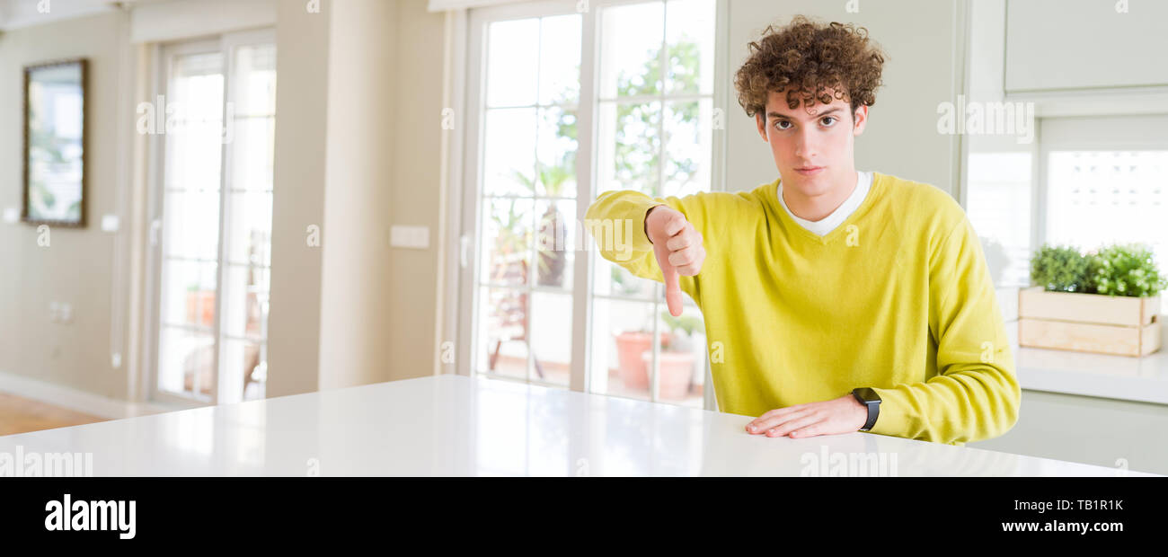Wide angle shot of young handsome man at home looking unhappy and angry ...