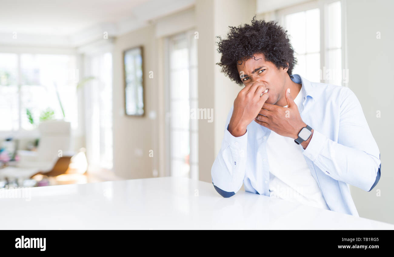 African American man at home smelling something stinky and disgusting ...