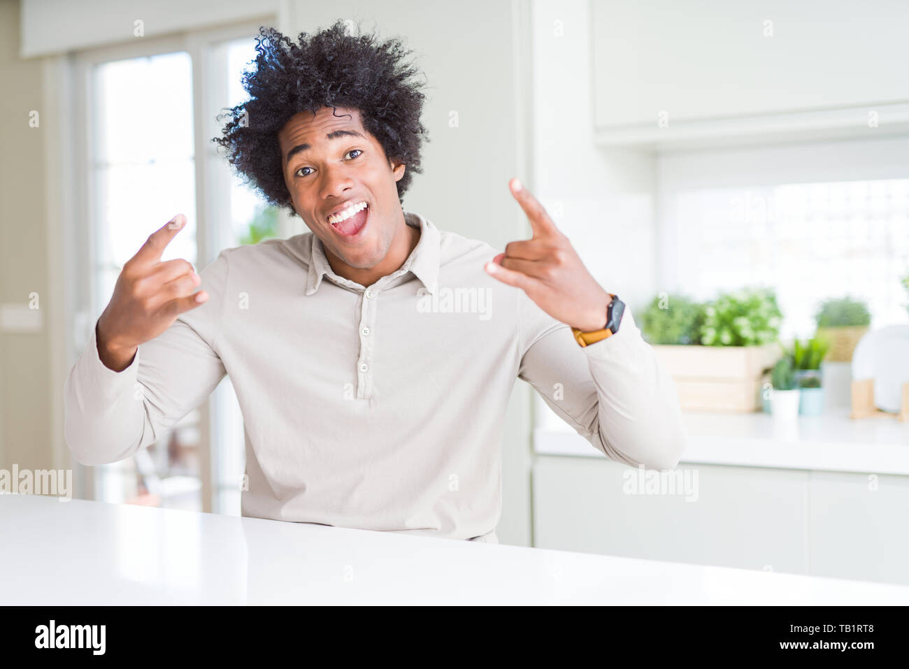African American man at home shouting with crazy expression doing rock ...