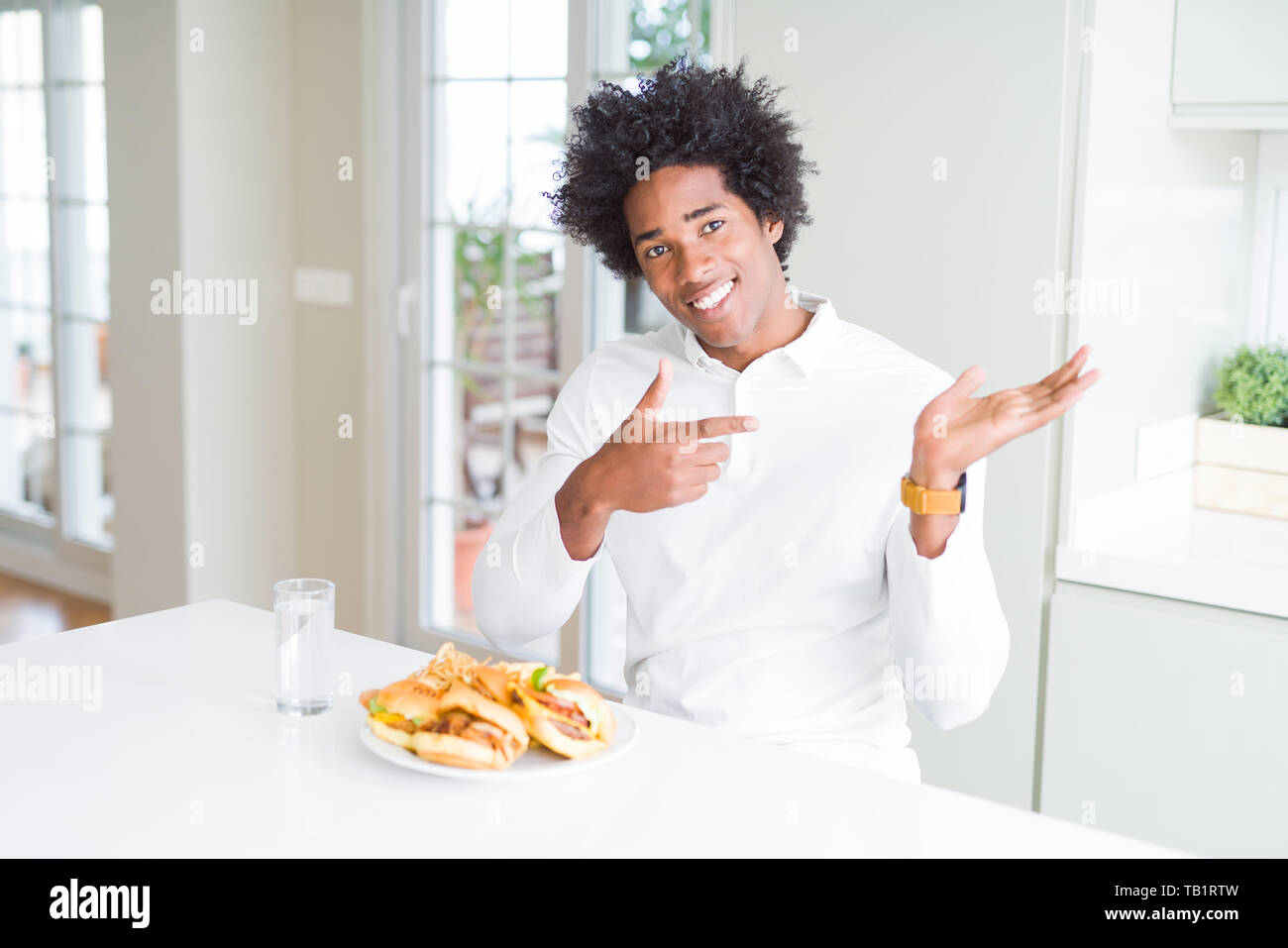 African American hungry man eating hamburger for lunch amazed and ...