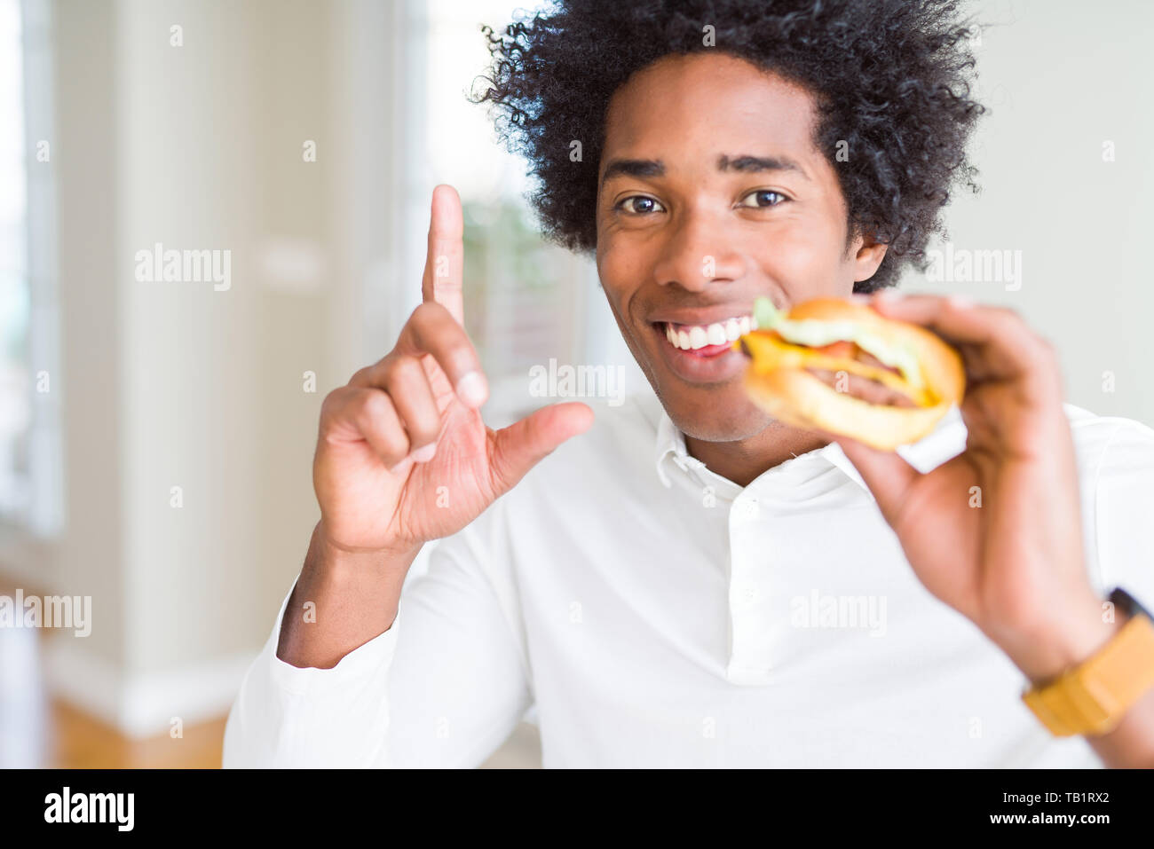 African American hungry man eating hamburger for lunch surprised with ...