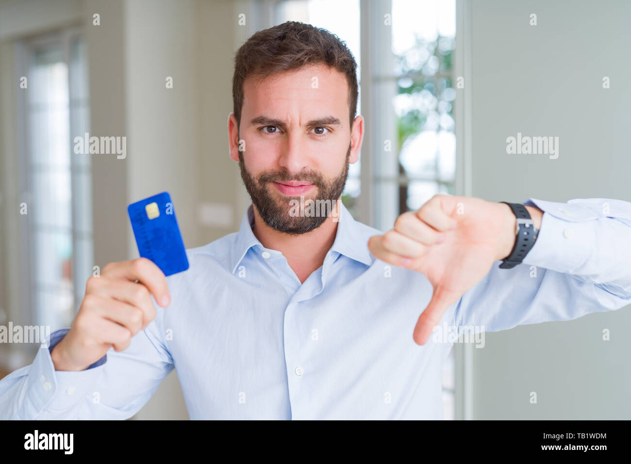 Handsome business man holding credit card with angry face, negative ...