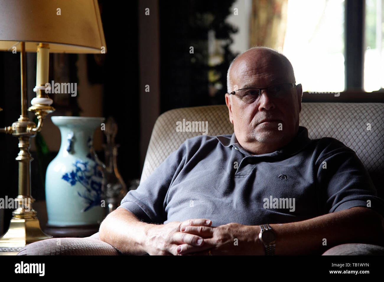 Portrait of an healthy elderly caucasian man sitting on his sofa inside ...