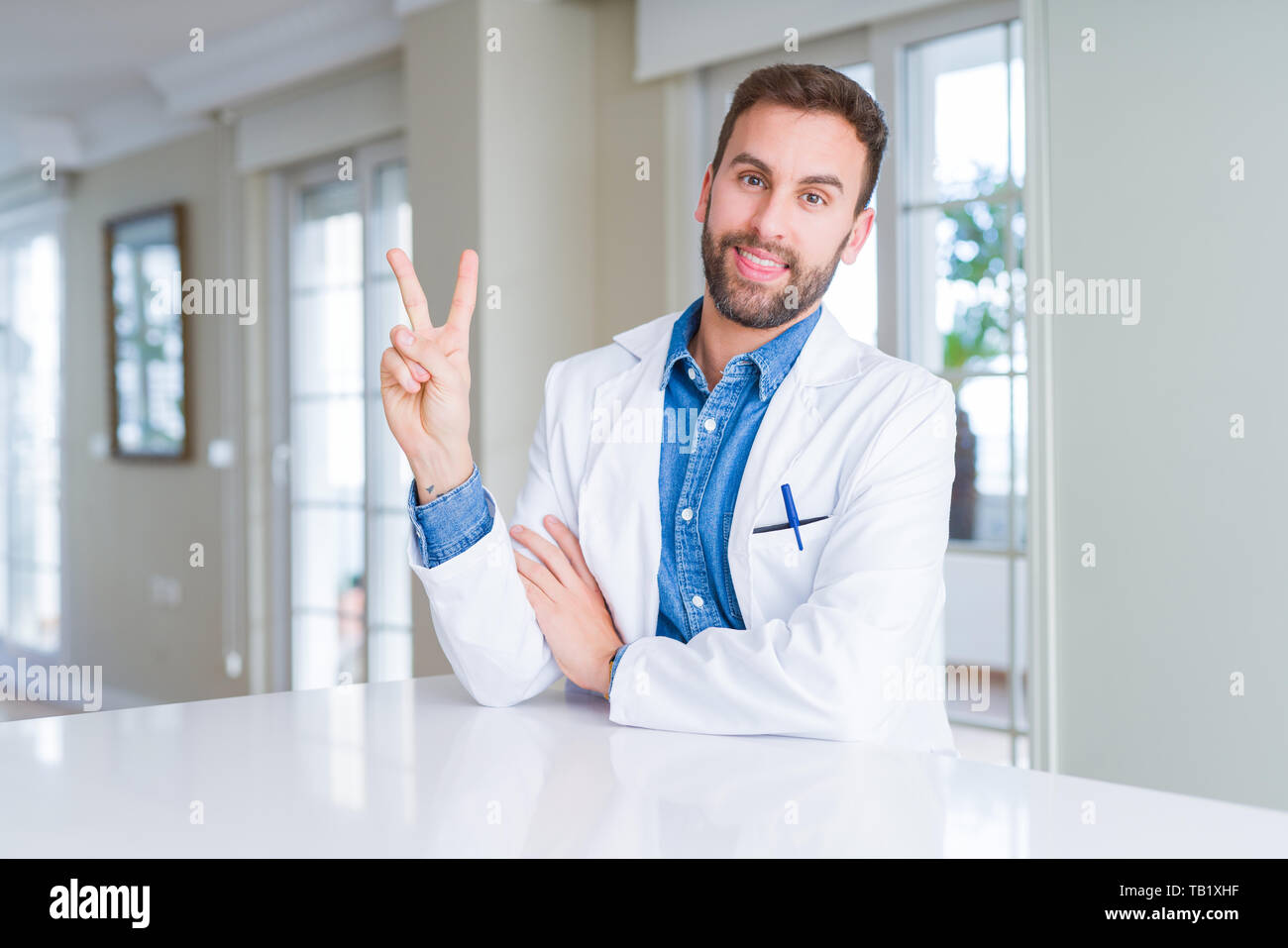 Handsome doctor man wearing medical coat at the clinic smiling with ...