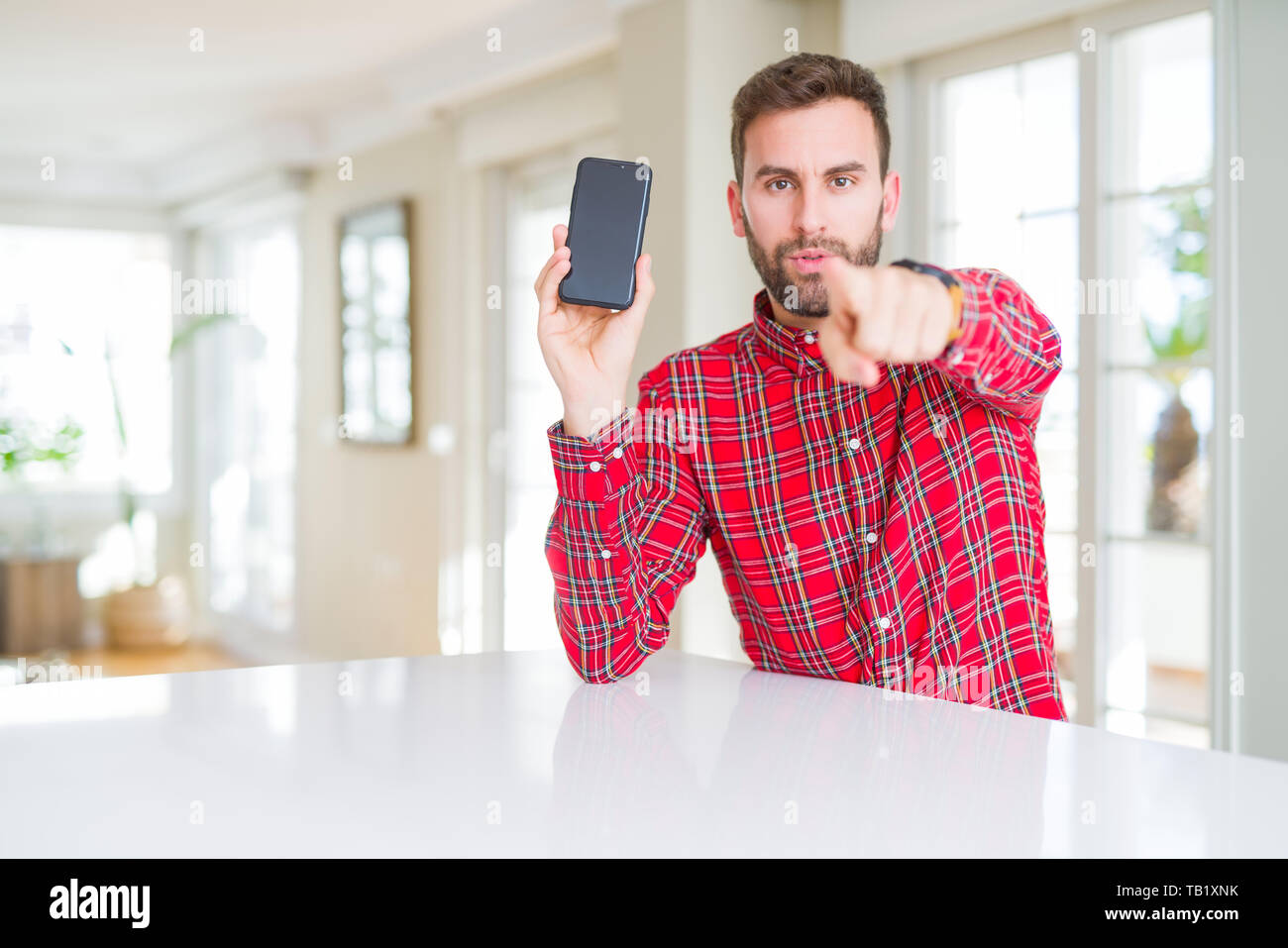 Handsome man showing smartphone screen pointing with finger to the ...