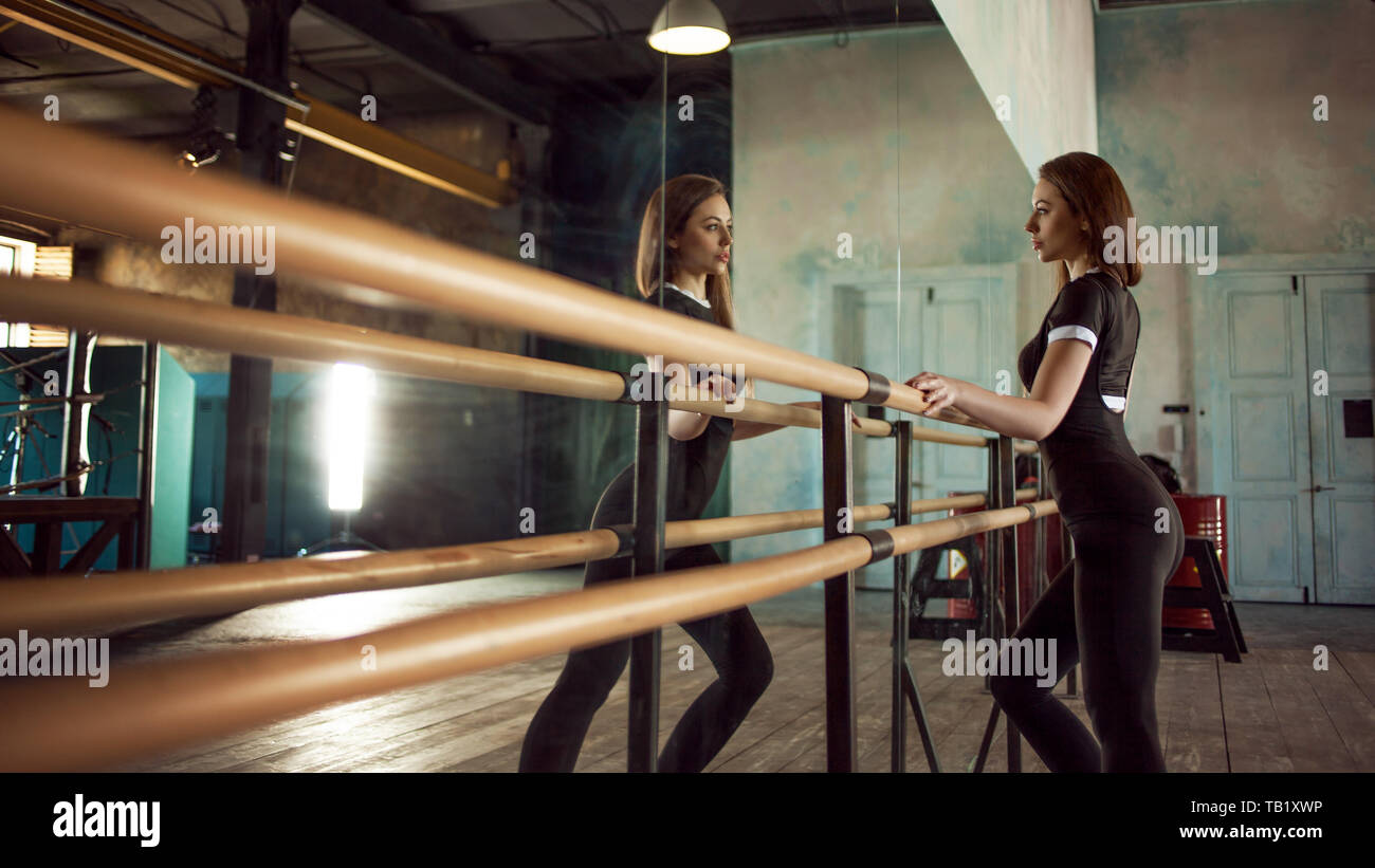 Young woman dancer near the ballet Barre in the dance hall. girl ...