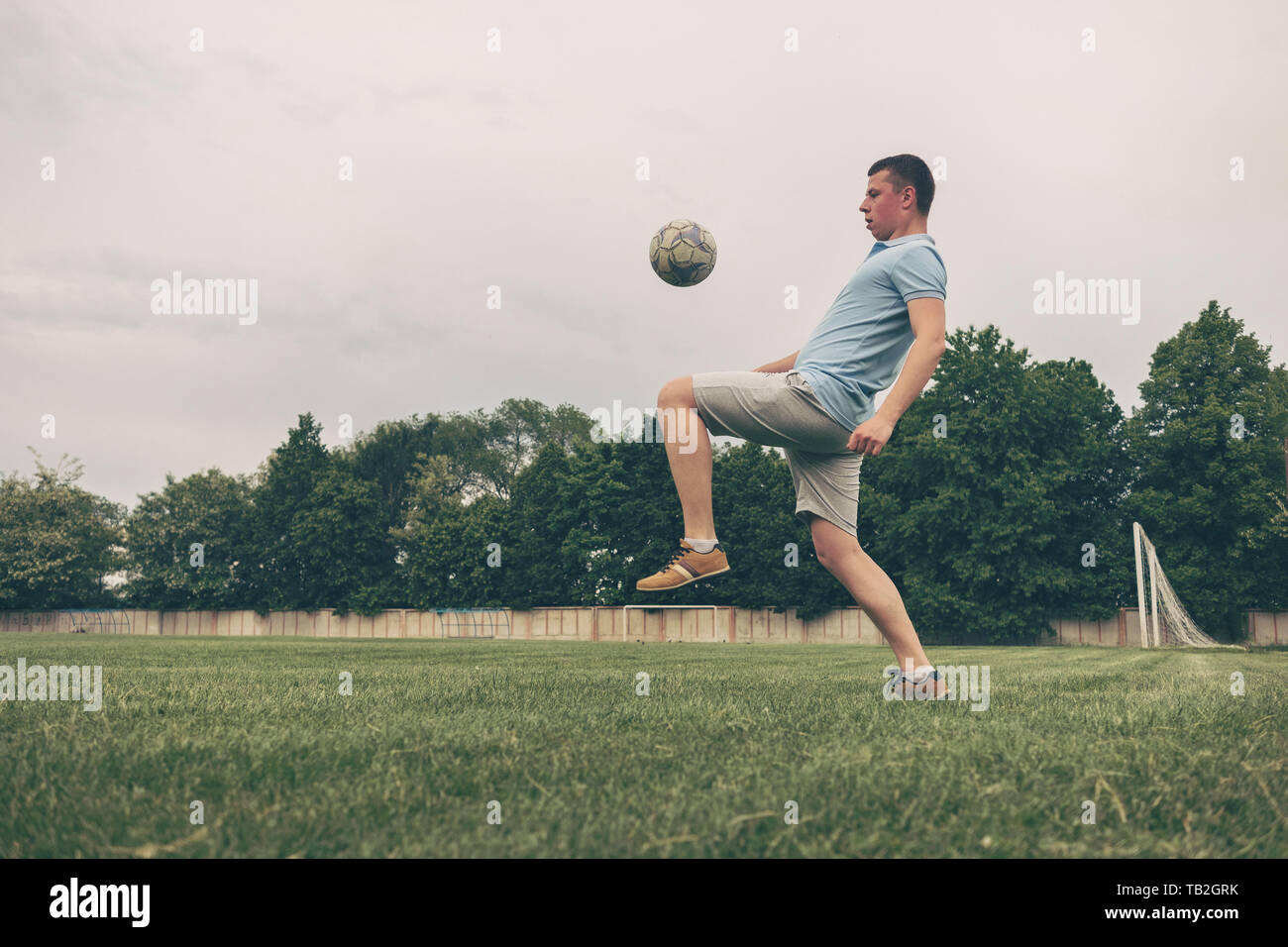 Young man practicing ball control and coordination bouncing a soccer ...