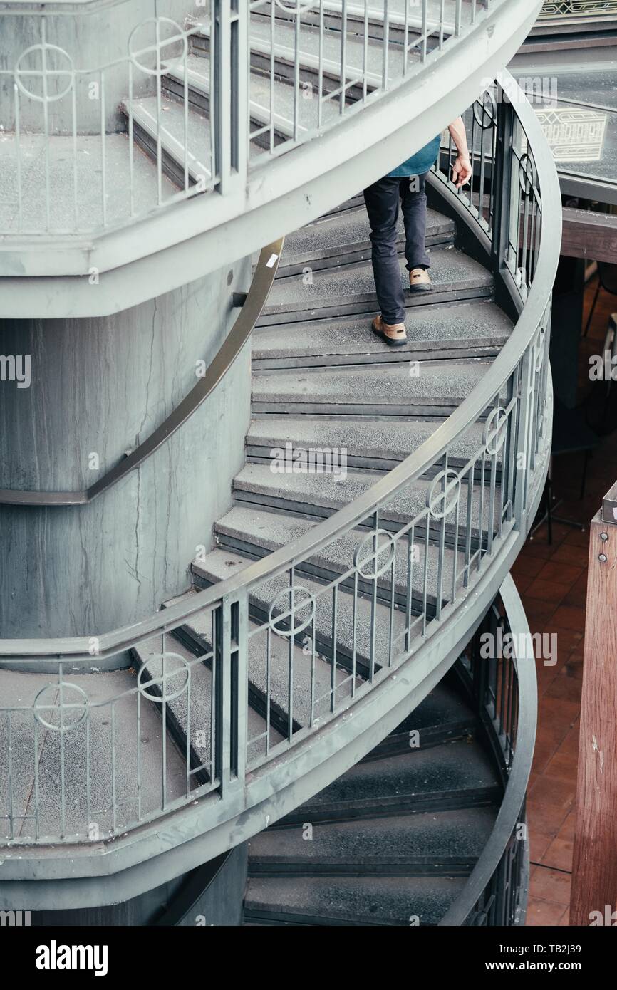 Person walking up a spiral staircase Stock Photo - Alamy