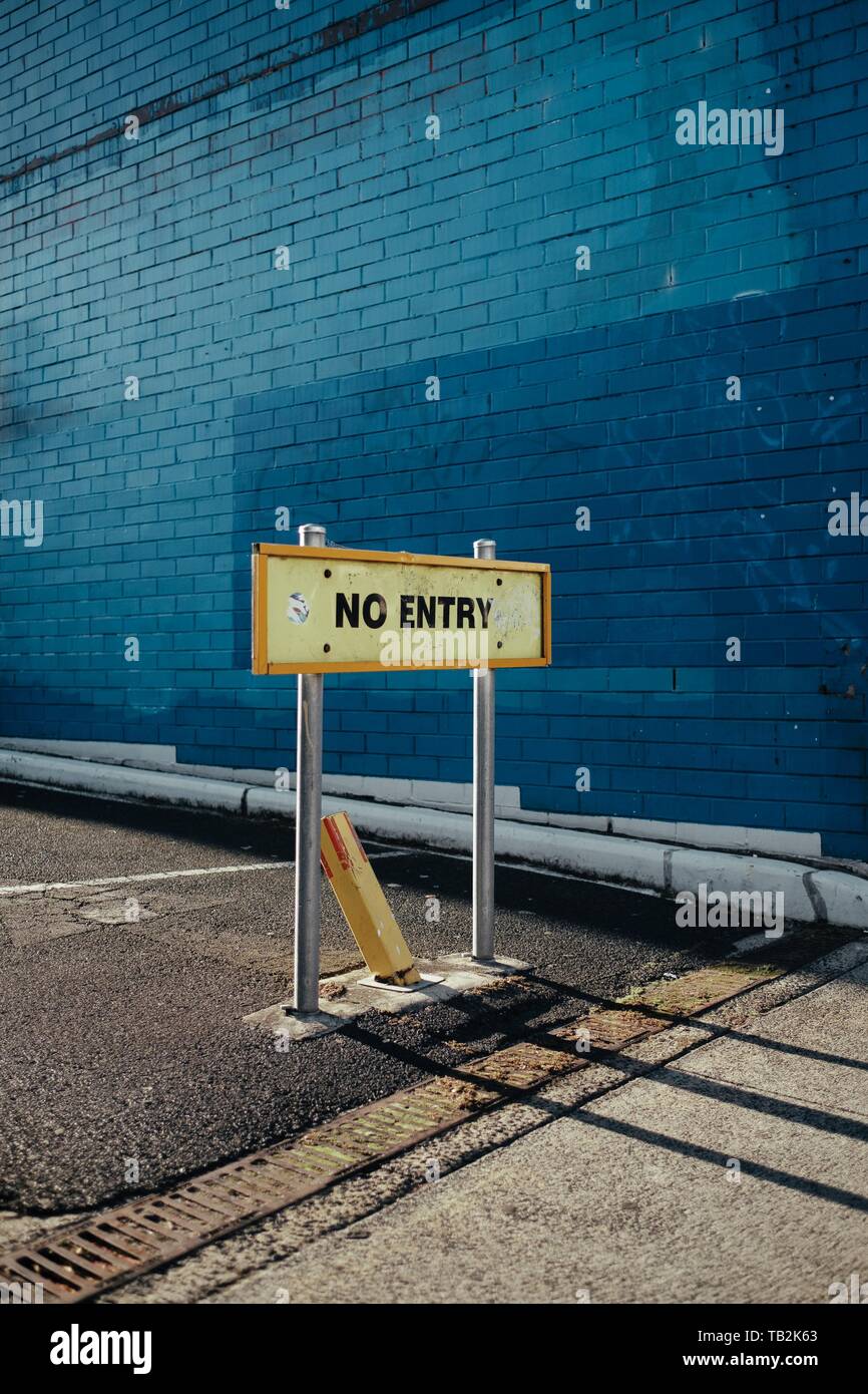 A sign that read "NO ENTRY" with a blue brick wall in background Stock ...