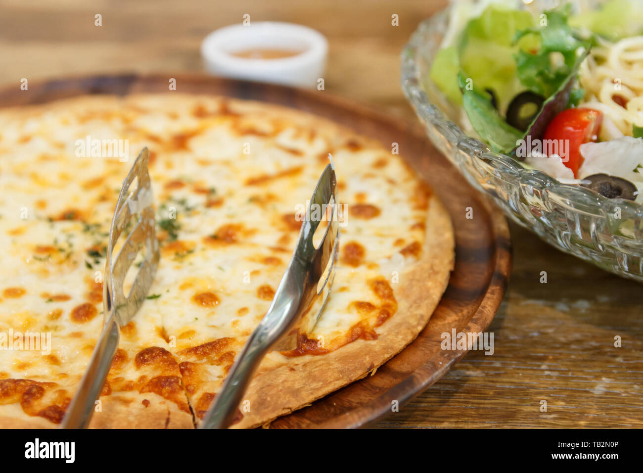 pizza with tongs for food and salad on the wooden table Stock Photo - Alamy