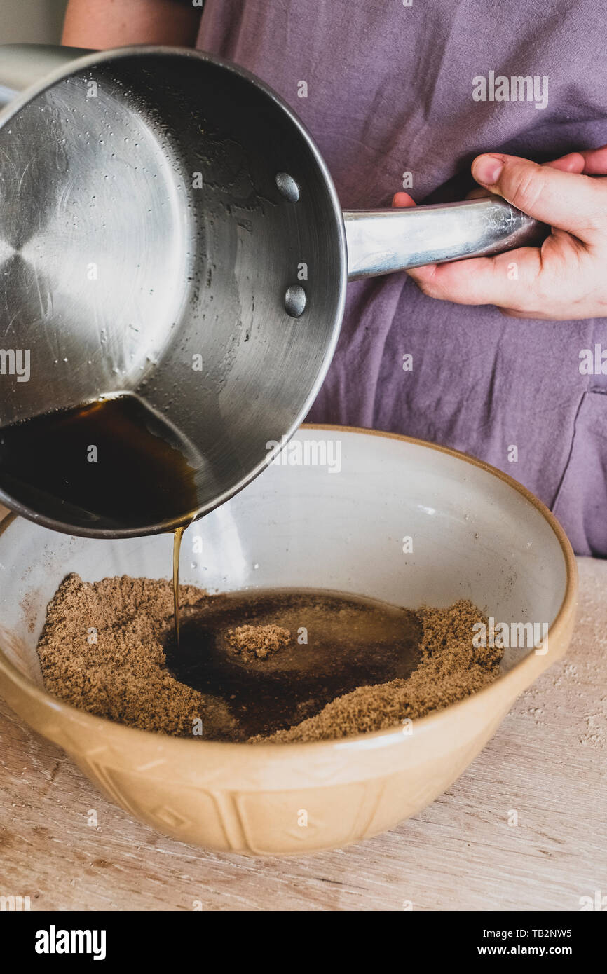 High angle close up of person pouring liquid into mixing bowl with ...