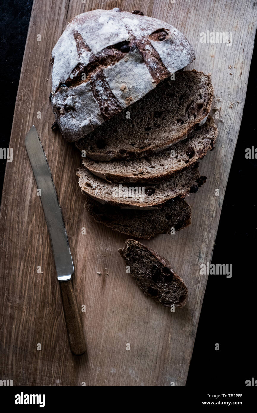 A round loaf of brown bread on a bread board partly sliced Stock Photo ...