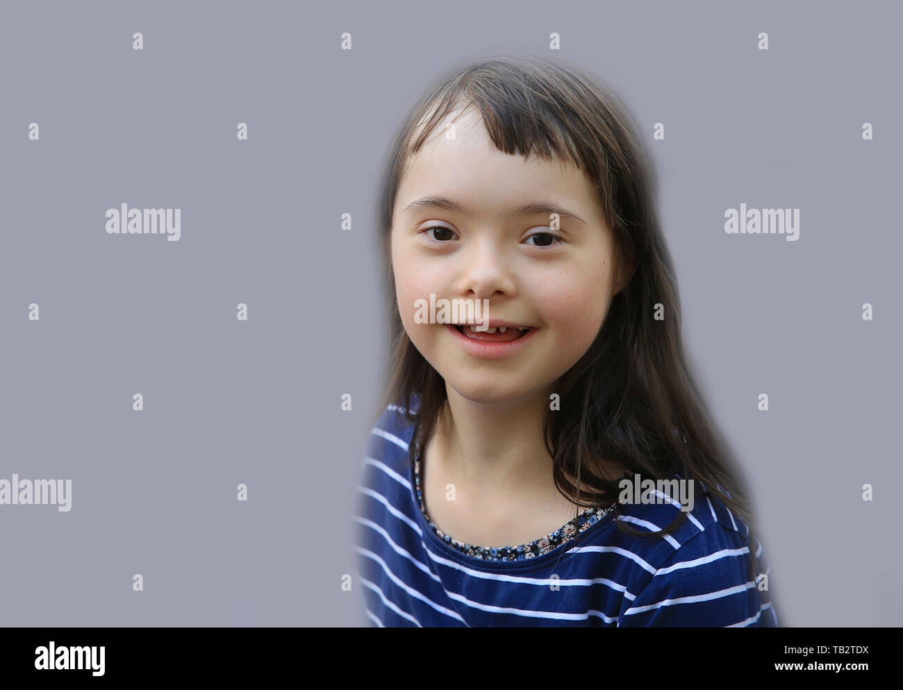 Cute down syndrome girl on the grey background Stock Photo - Alamy