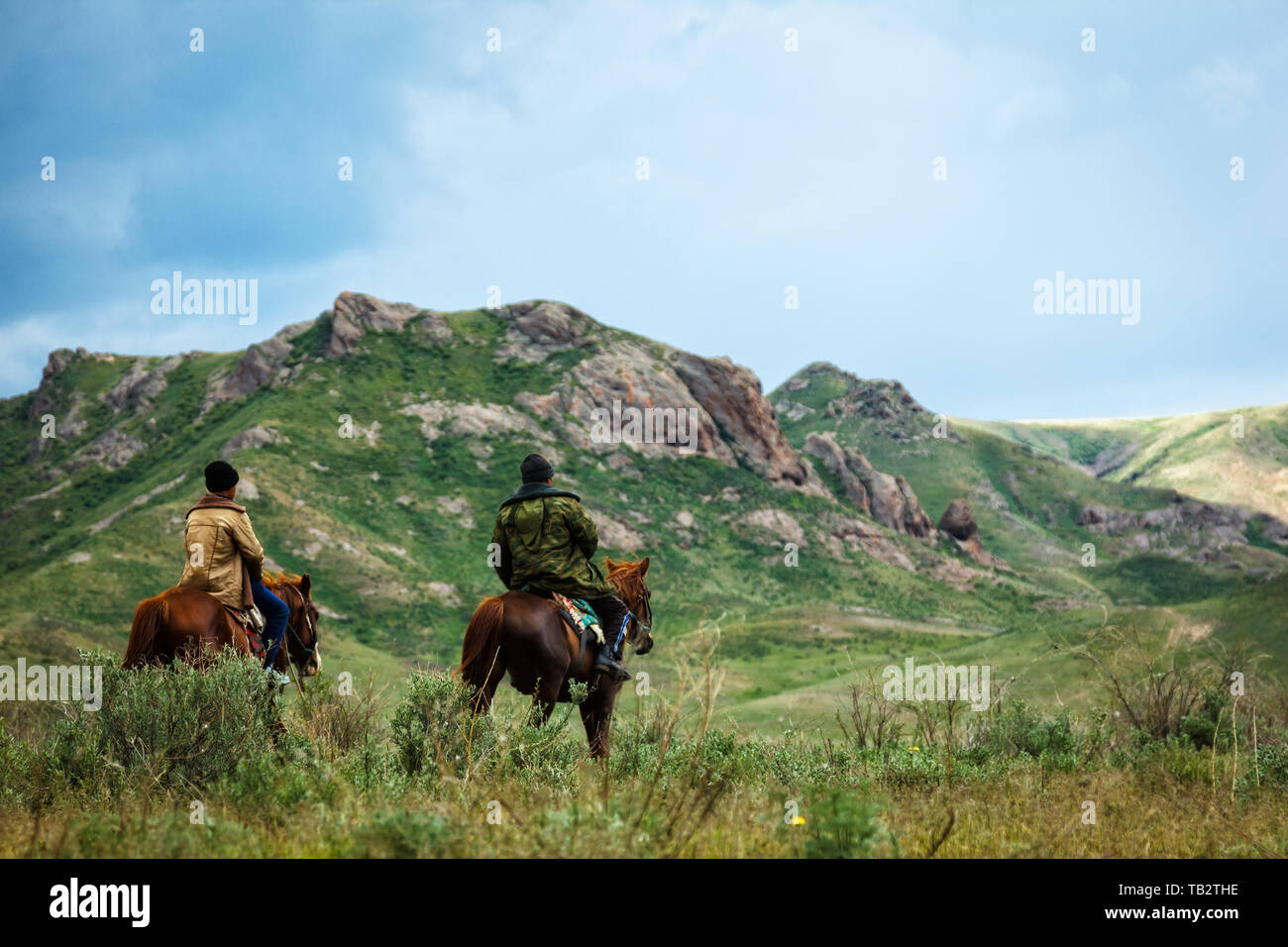 Two men riding horses. Summer pastures in an intermontane valley ...