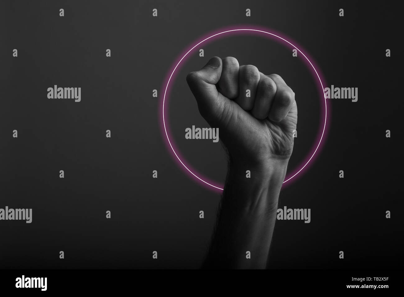 Raised clenched fist against a dark background with abstract neon light ...