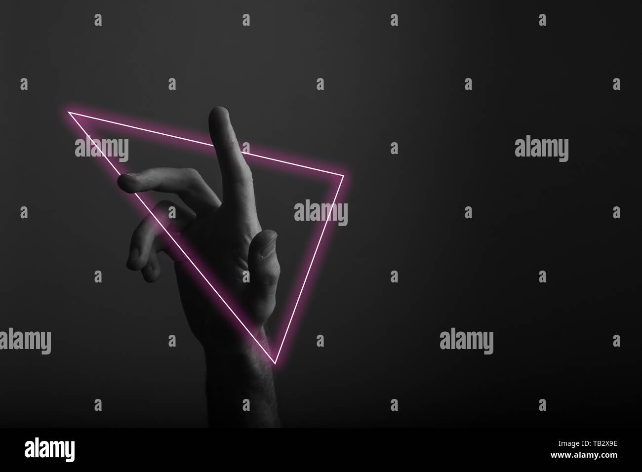 Hand pointing a finger against a dark background with abstract neon ...