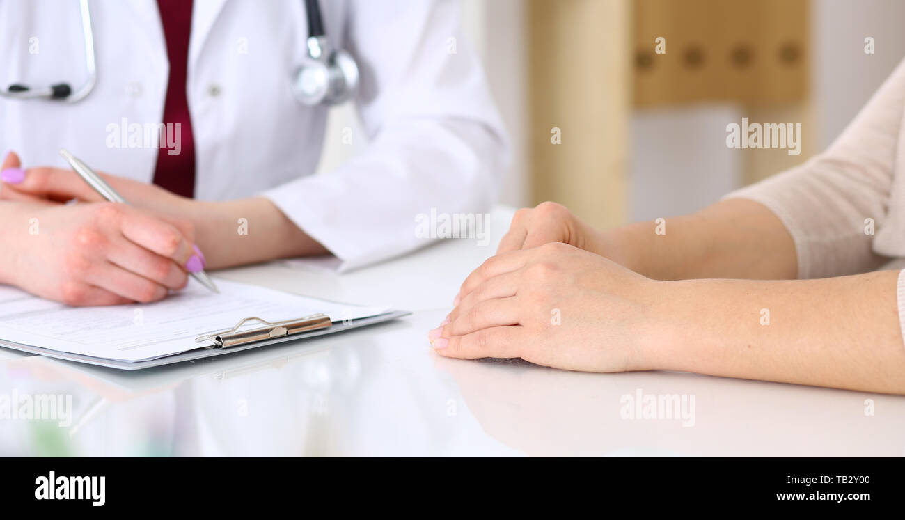 Unknown doctor woman consulting patient while filling up an application ...