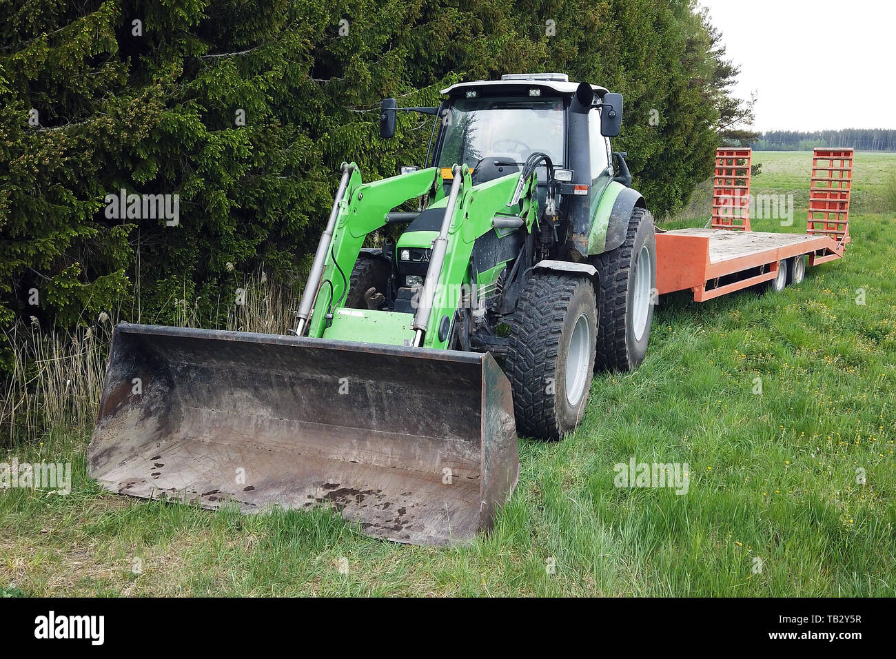Front view of tractor with front end loader and trailer for excavator ...