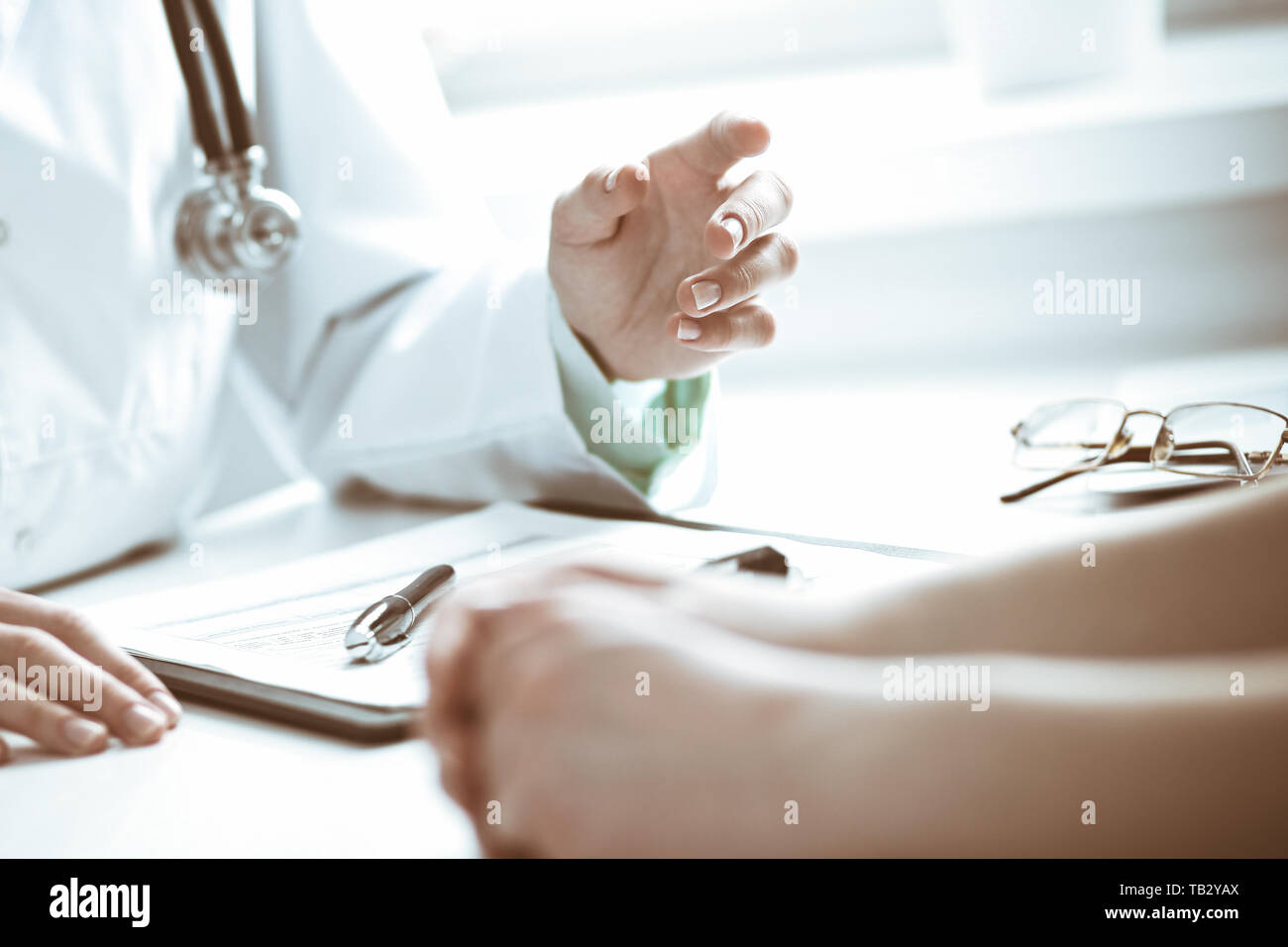 Doctor and female patient sitting at the desk and talking in clinic ...