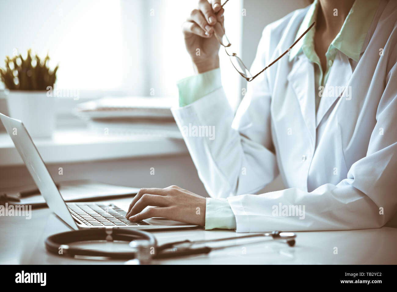 Doctor woman using laptop computer while sitting at the desk near ...