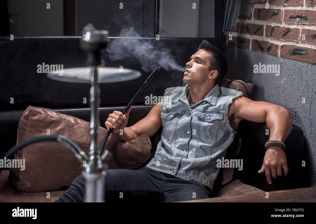 Young handsome man blowing clouds of smoke at a coffee shop. The ...