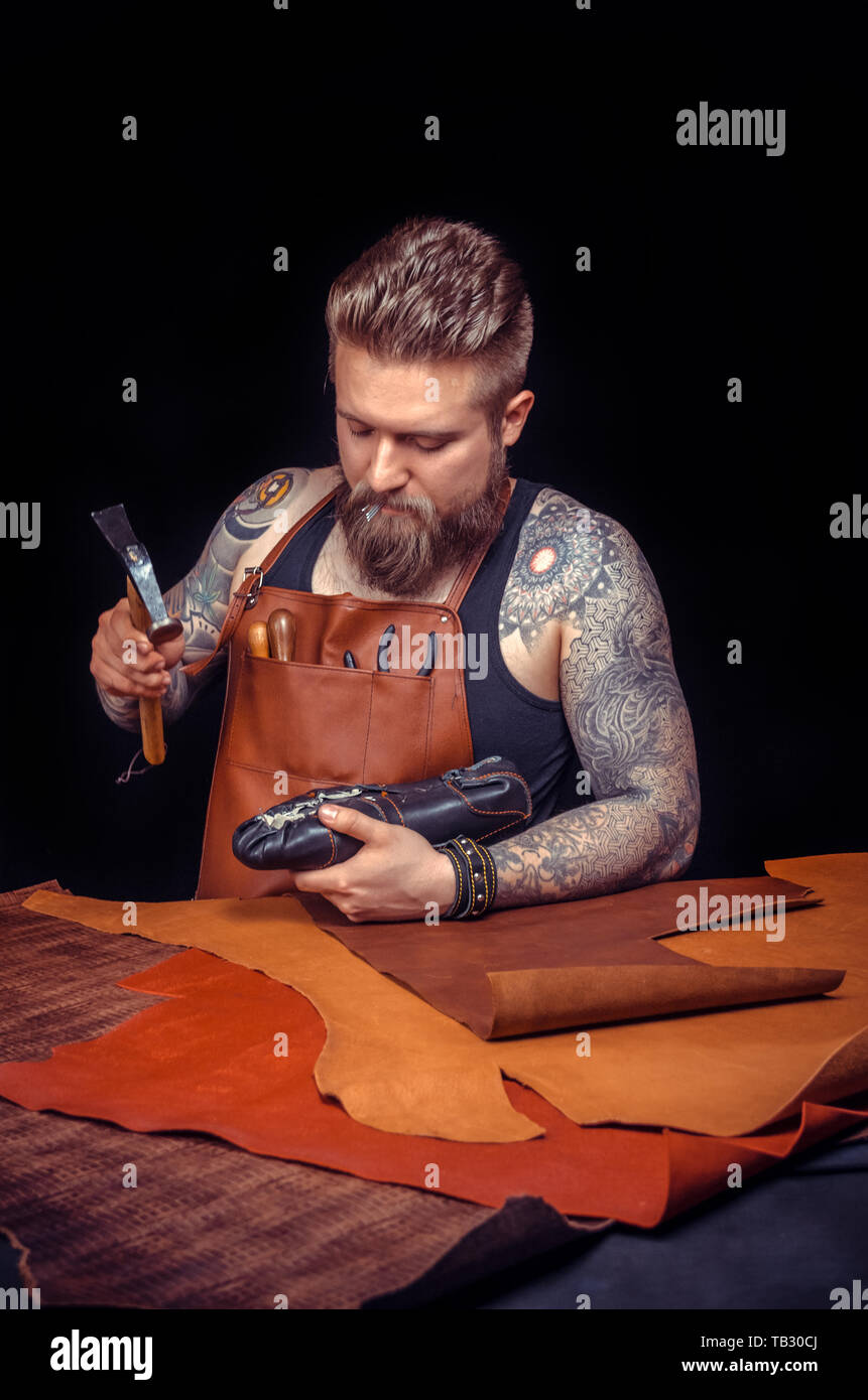 Currier of leather cutting out leather goods at the place of work Stock ...