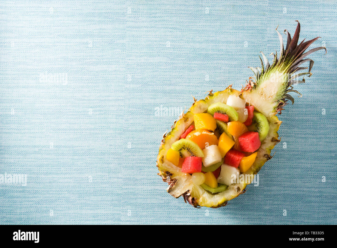 Mix fruit served inside pineapple on blue background Stock Photo - Alamy