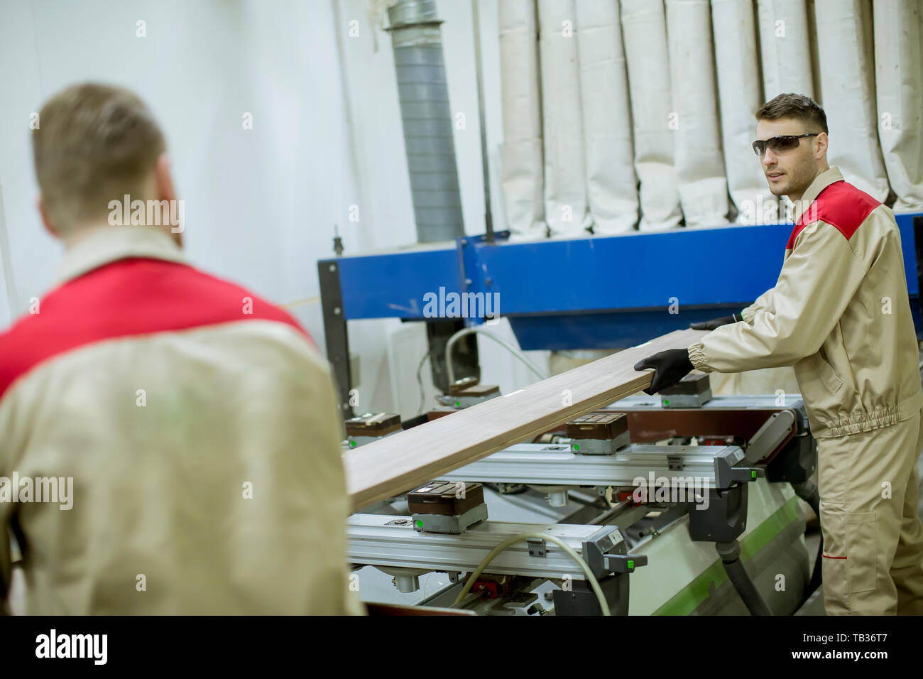 Two handsome young men working in the furniture factory Stock Photo - Alamy