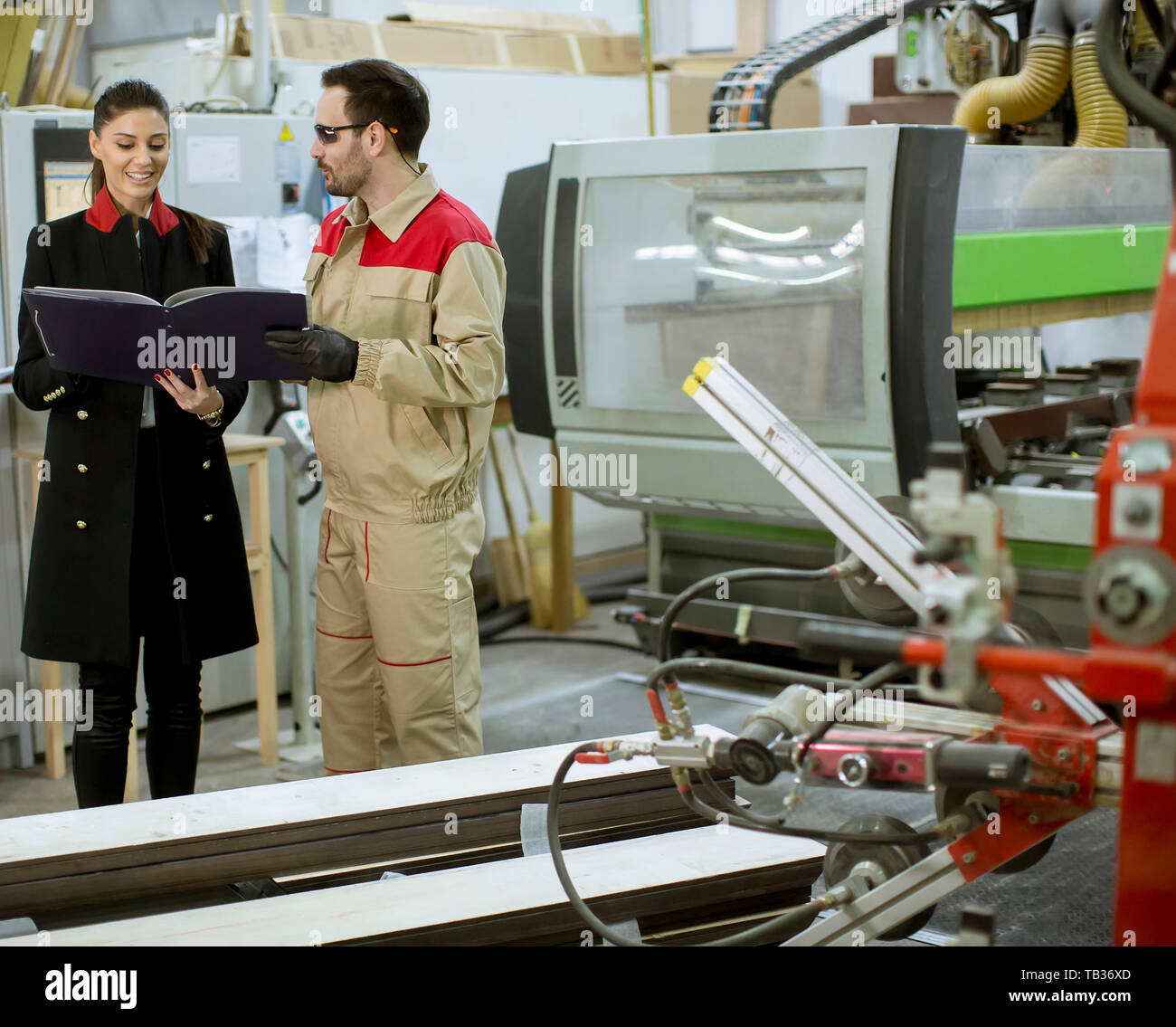 Pretty young woman controlling process in the factory with male worker ...
