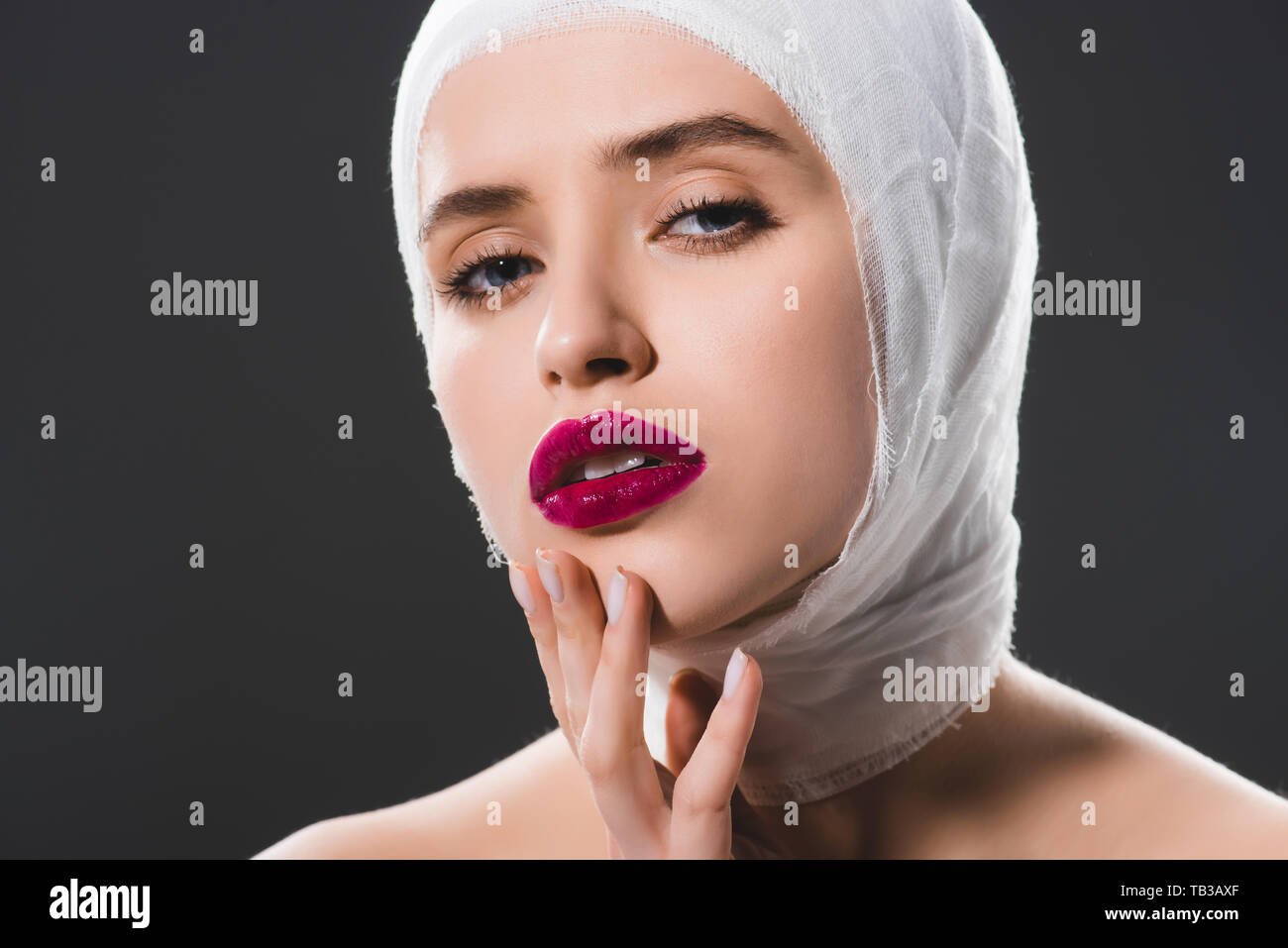 attractive young woman with bandaged head touching face and looking at ...