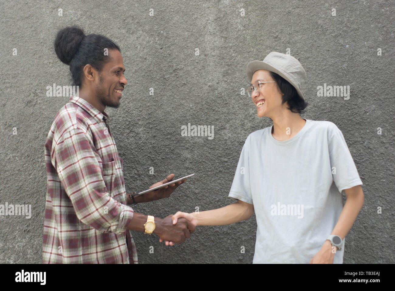 young asian man hand shaking with young black man while smiling each ...