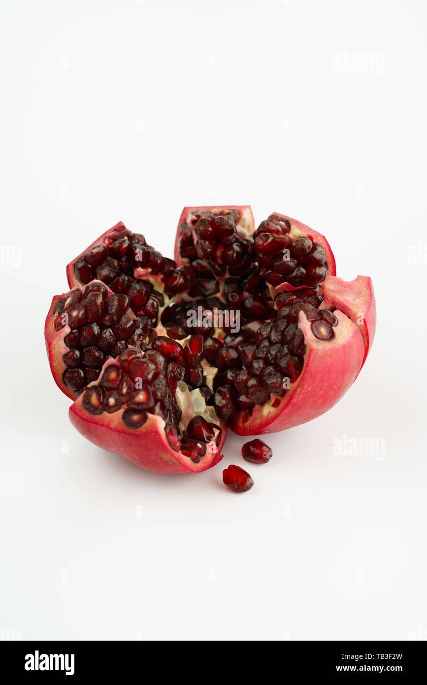 Organic pomegranate, cut open, seeds. White background, high resolution ...