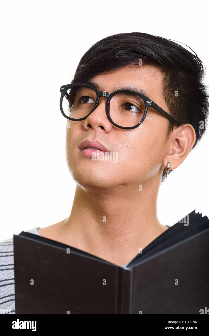 Face of handsome Asian man holding book while thinking Stock Photo - Alamy