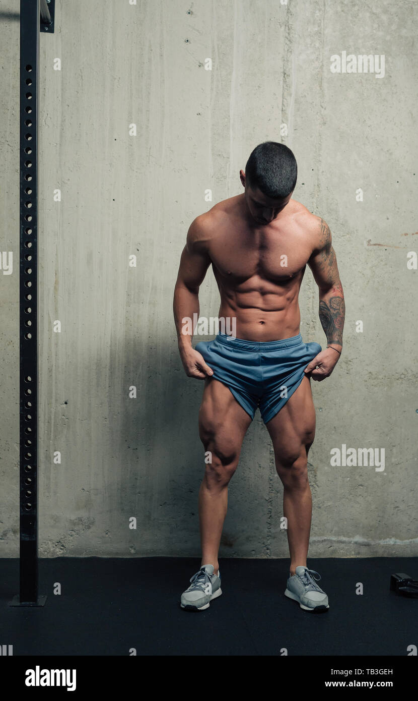 Young strong man posing and flexing his quadriceps legs muscles in a gym Stock Photo - Alamy