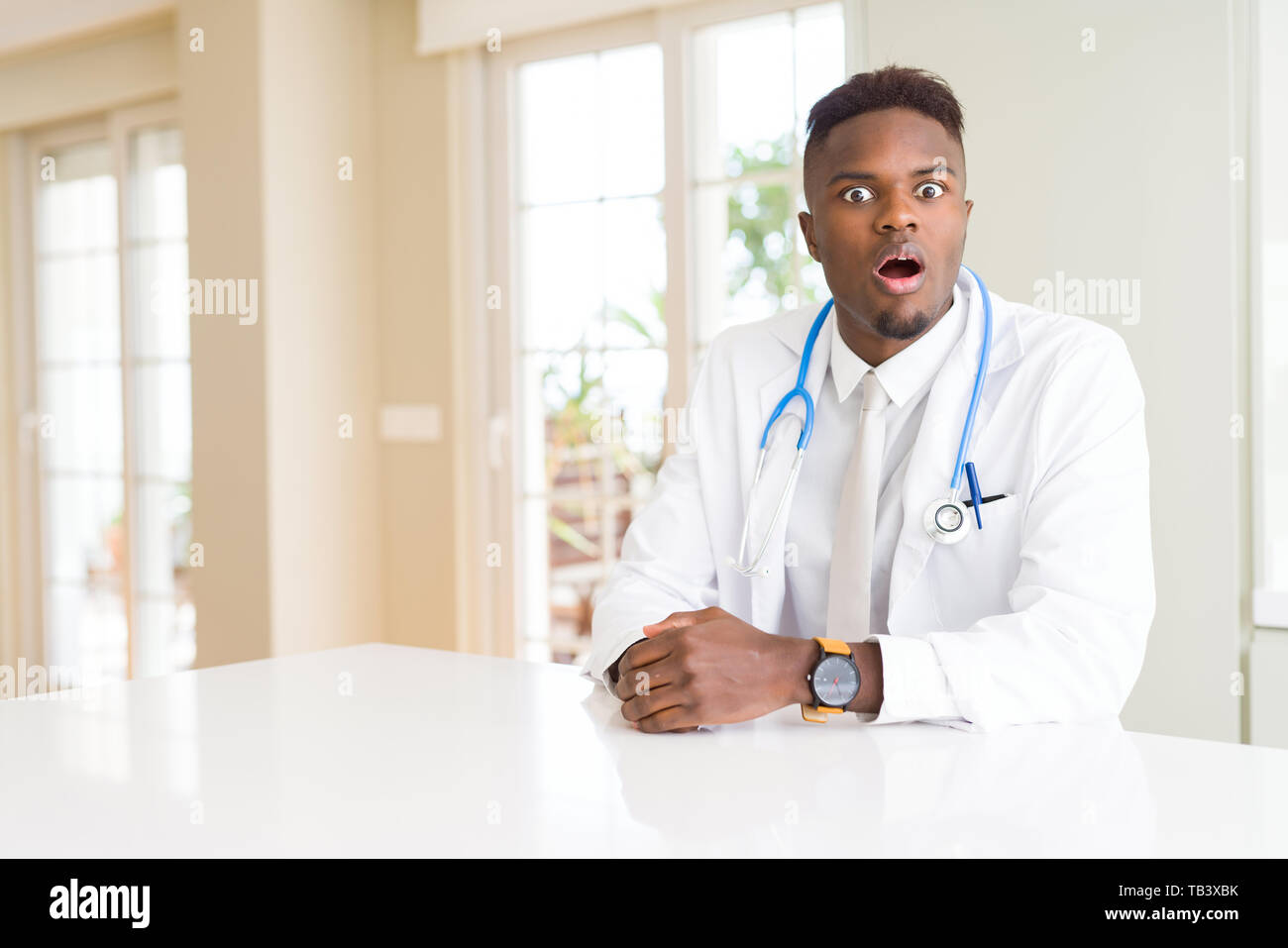 African american doctor man at the clinic afraid and shocked with ...