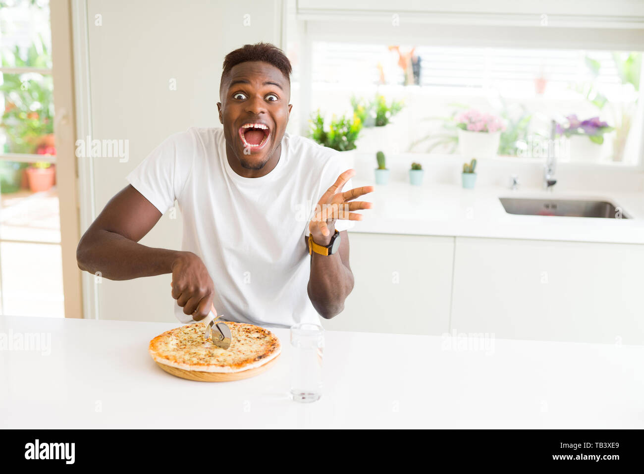 African american man eating cheese pizza at home very happy and excited ...