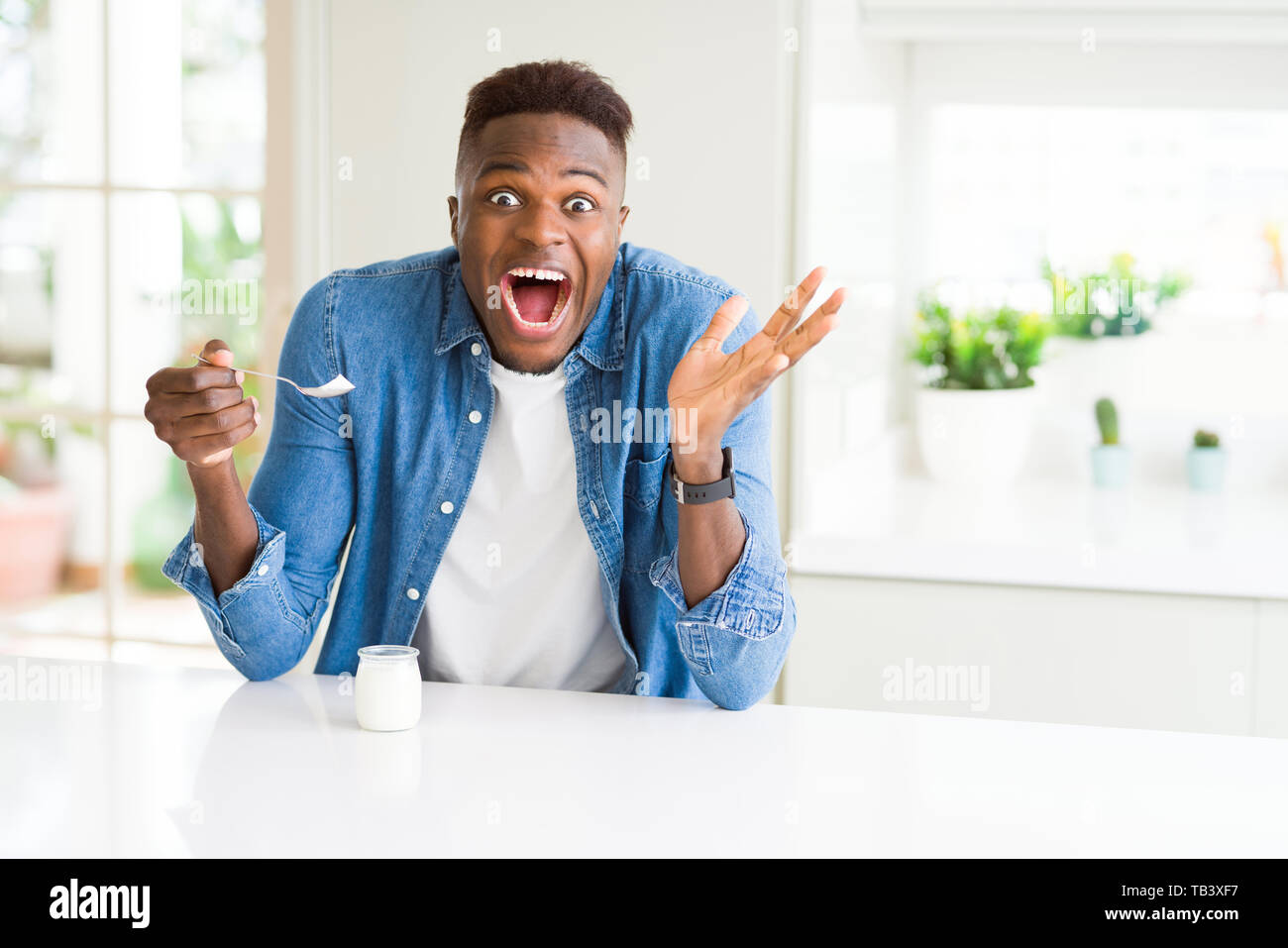 African american man eating healthy natural yogurt with a spoon very ...