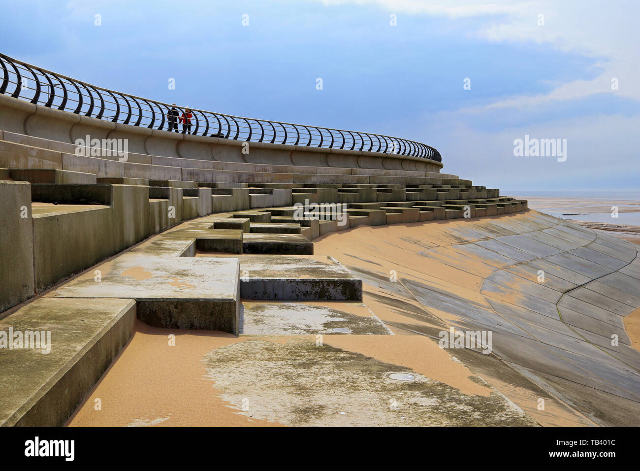 Distant figures add life to the promenade above the new sea defences at ...