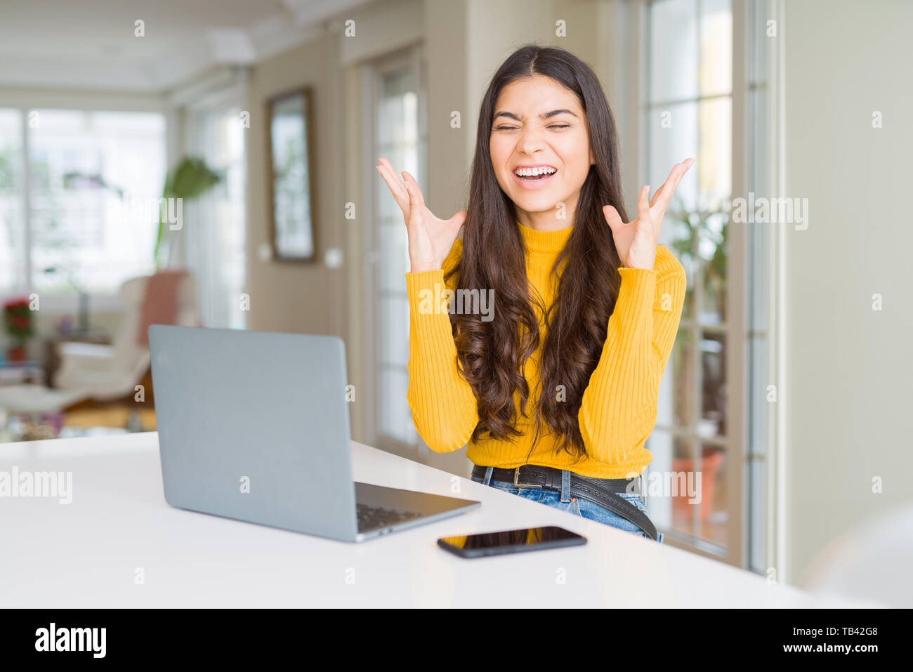 Young woman using computer laptop celebrating mad and crazy for success ...