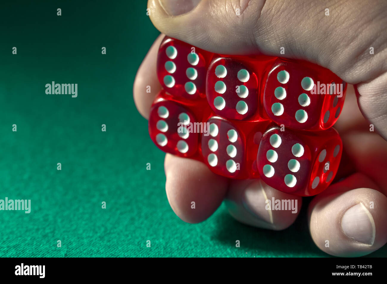 Closeup of hand holding red dice with a winning combination on green ...