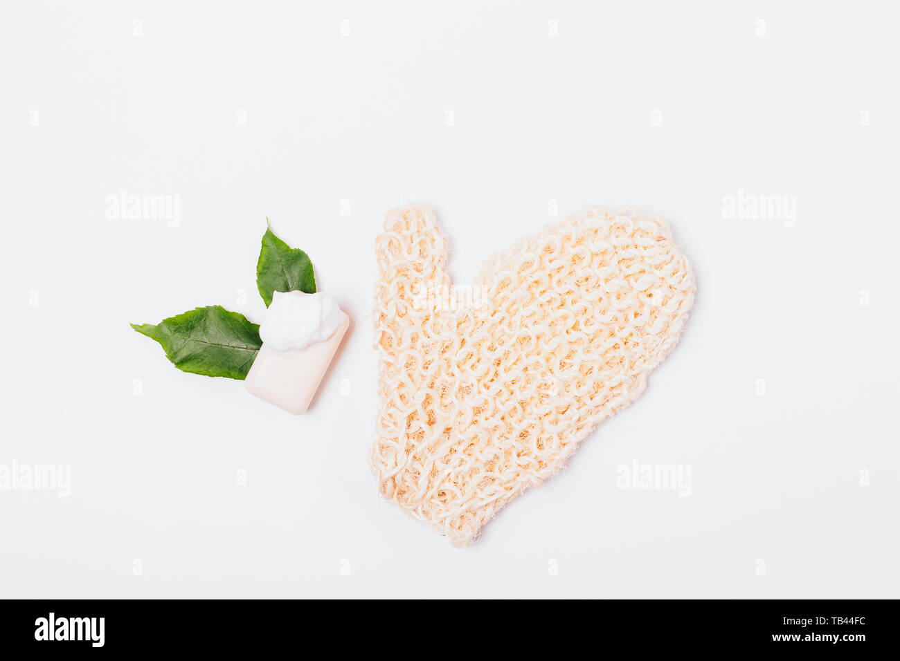 Foamed bath soap with green leaves and massage sponge mitten on white ...
