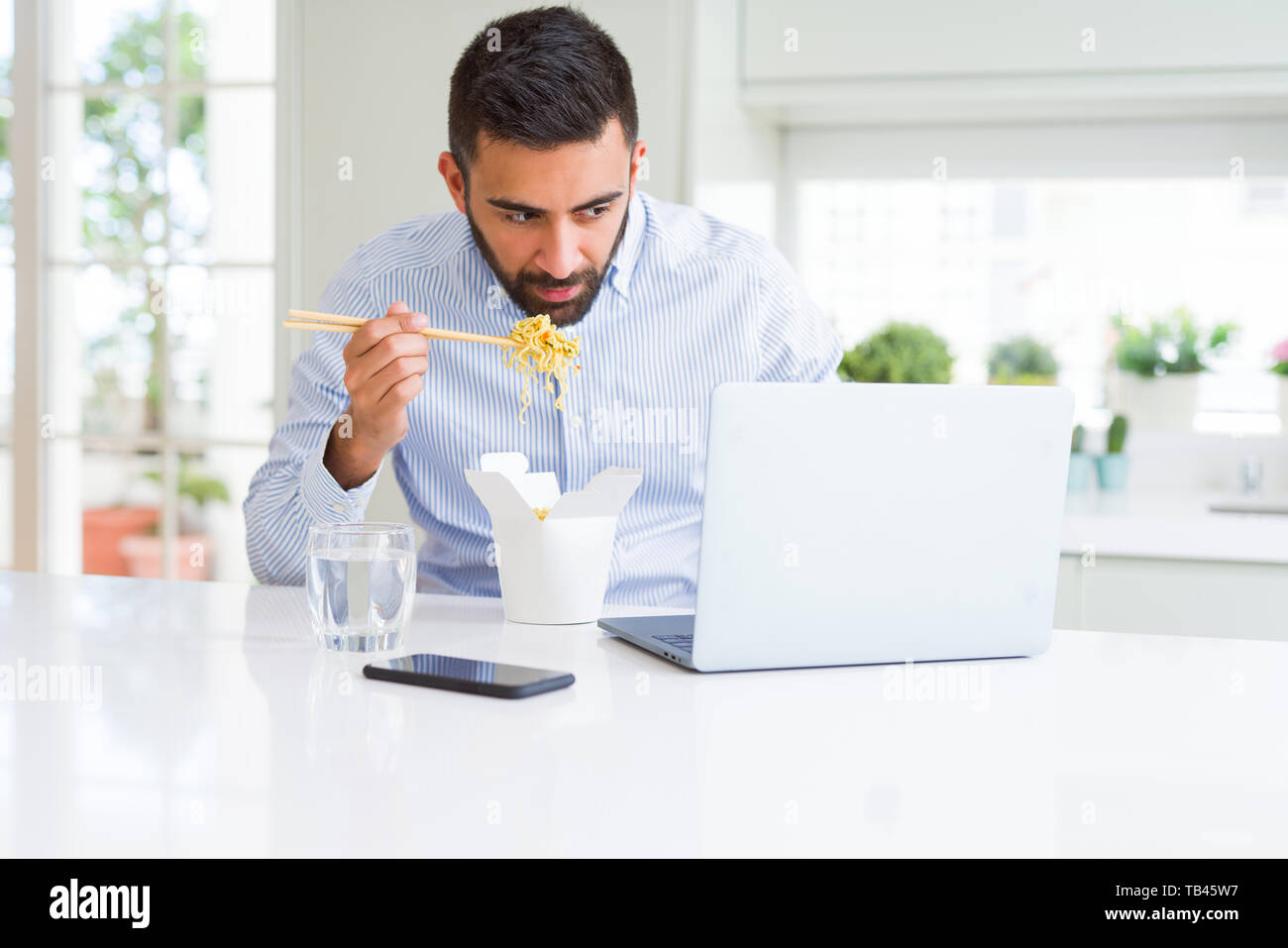 Business man eating asian food from delivery while working using ...