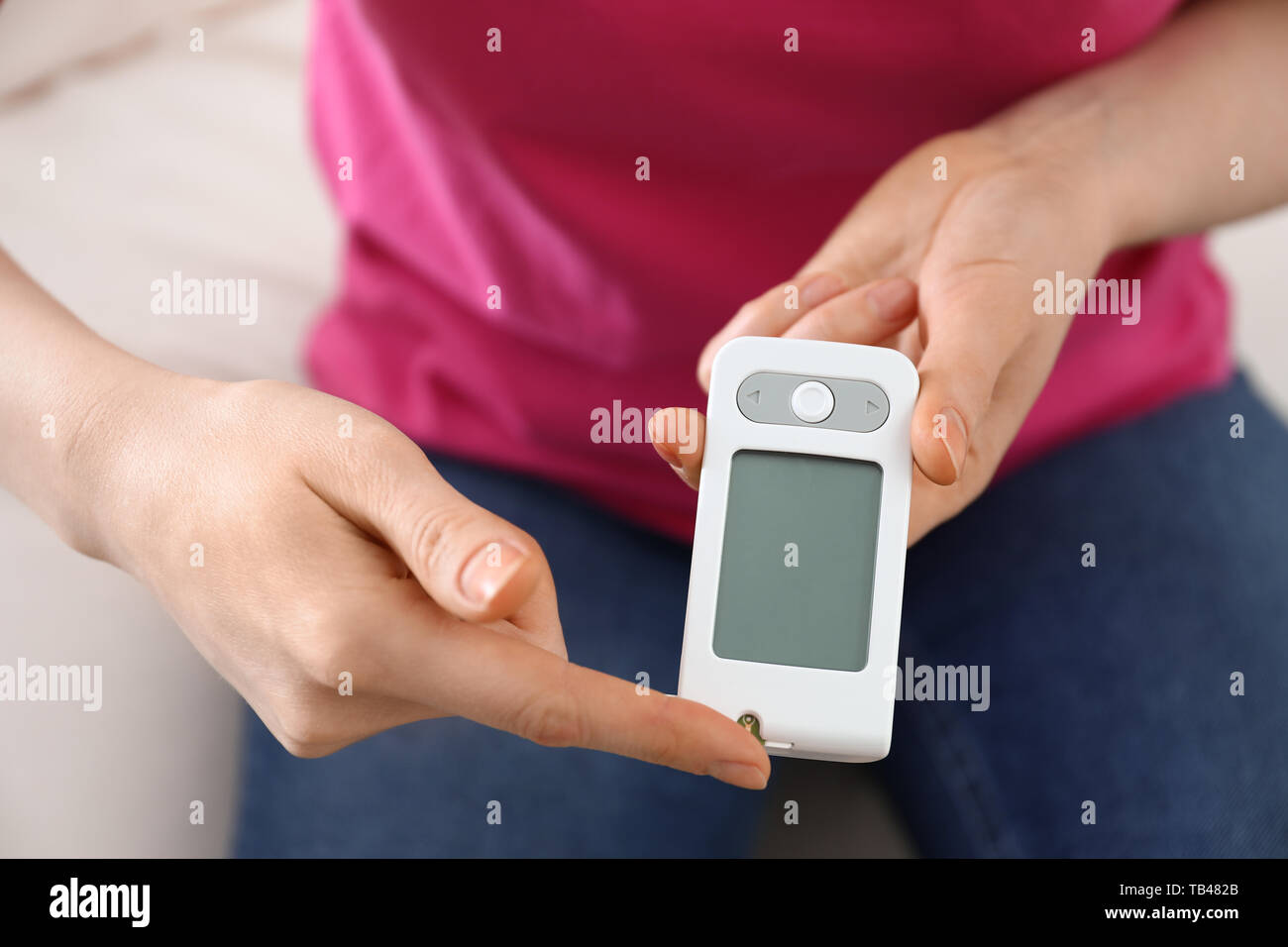 Diabetic woman measuring blood sugar level with digital glucometer at ...