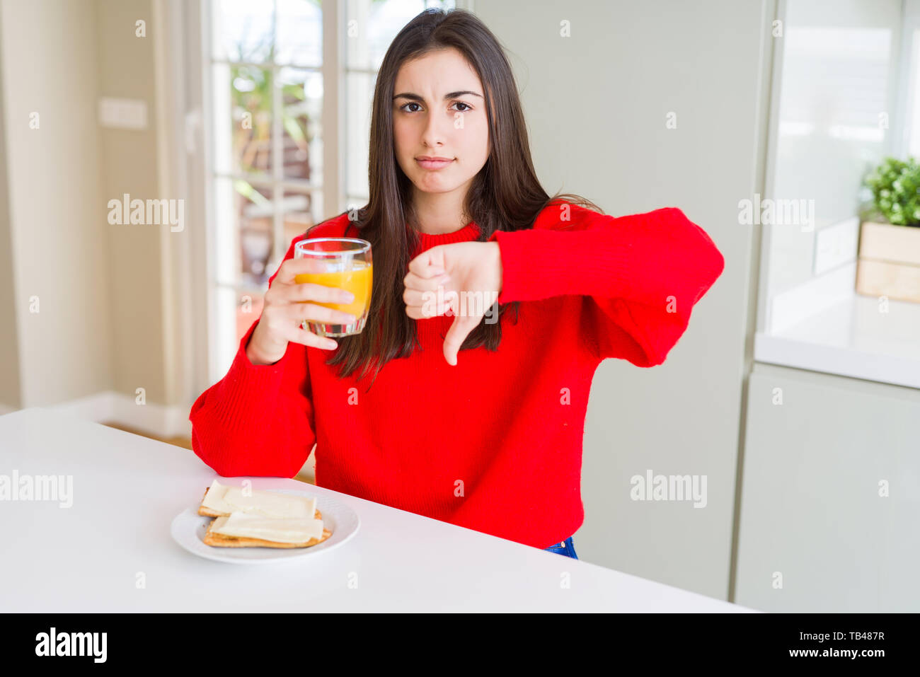 Beautiful young woman eating toasts and orange juice for snack or ...