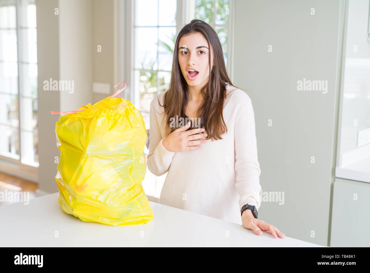 Beautiful young woman taking out the garbage from the rubbish container ...